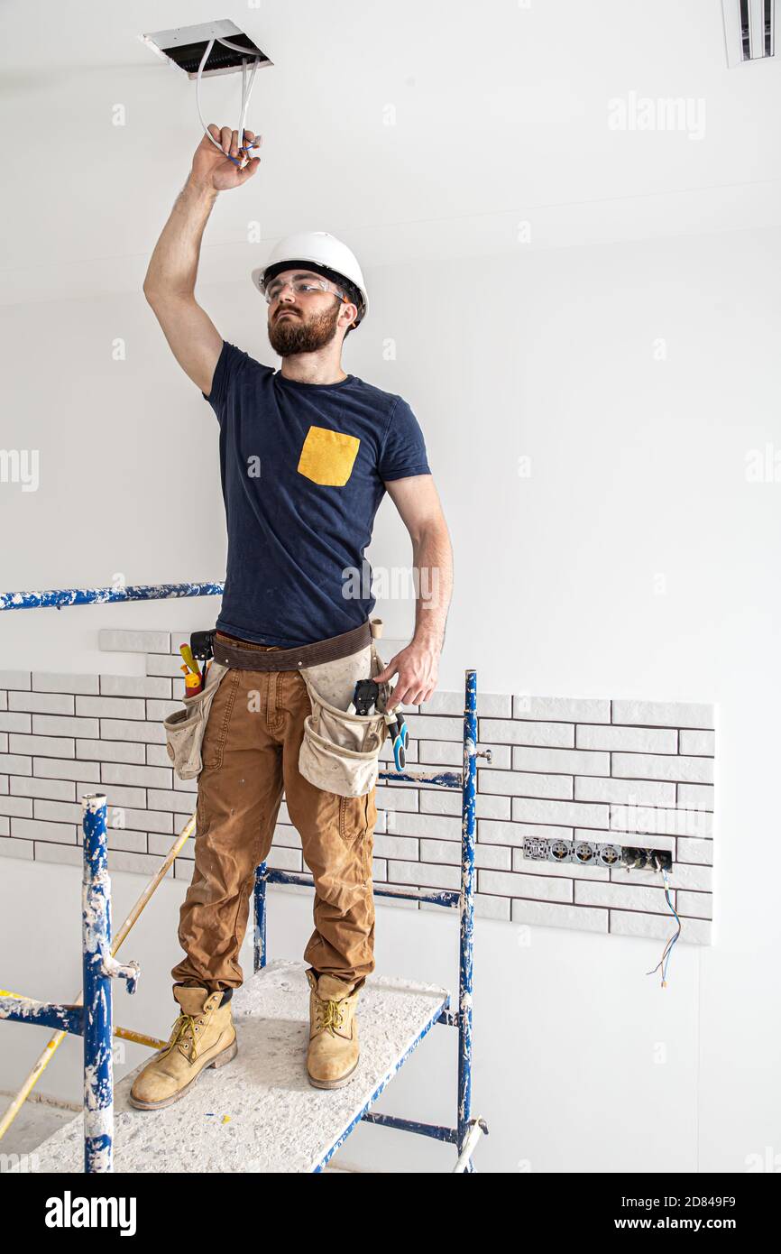 Electrician Builder at work, installation of lamps at height ...