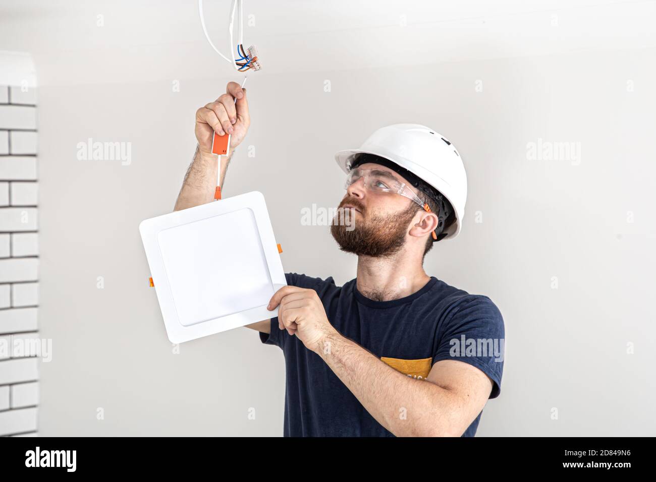 Electrician Builder at work, installation of lamps at height ...