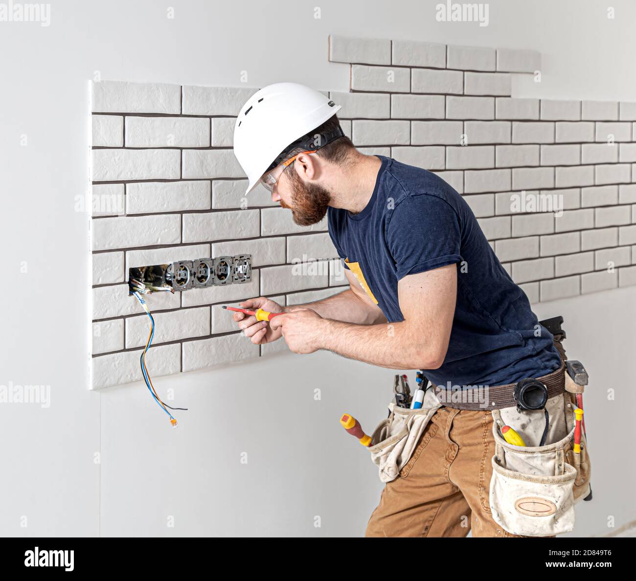 Electrician Builder at work, installation of sockets and switches ...