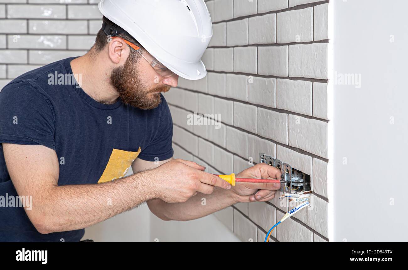 Electrician Builder at work, installation of sockets and switches ...