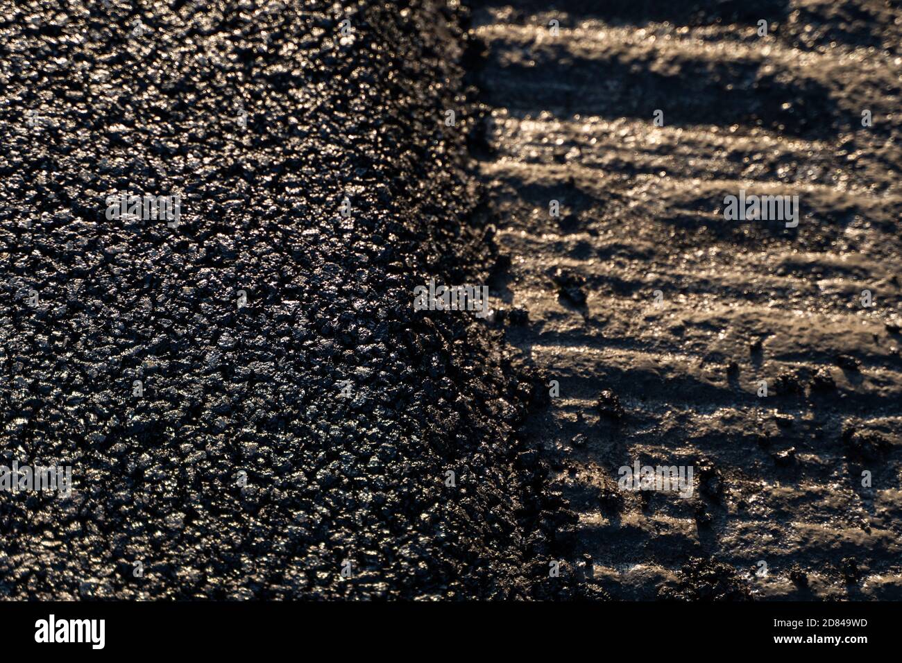 Freshly laid black bitumen asphalt with a high edge to the gravel ...