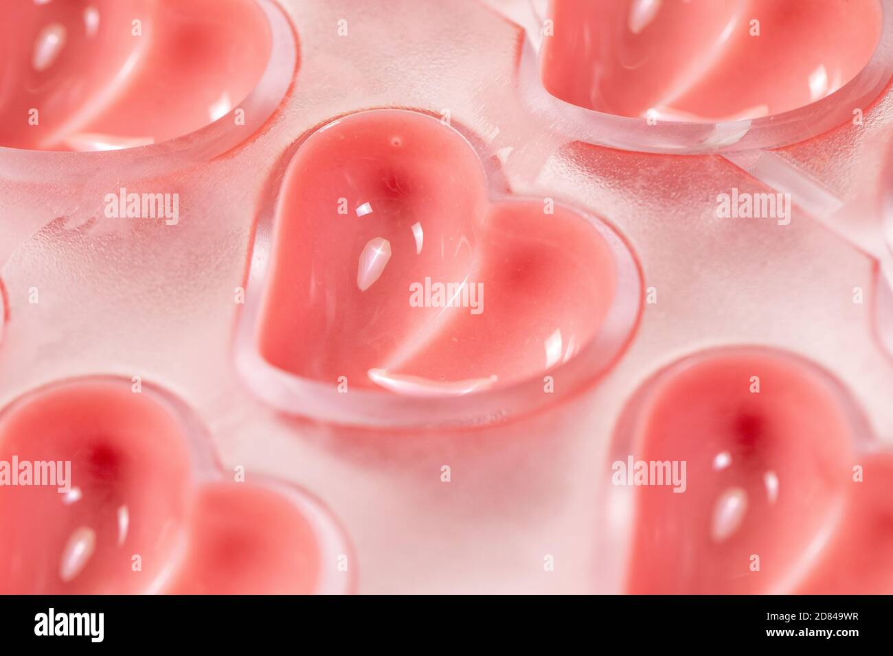 Love pink background, closeup heart shape confectionery mold with ruby ...