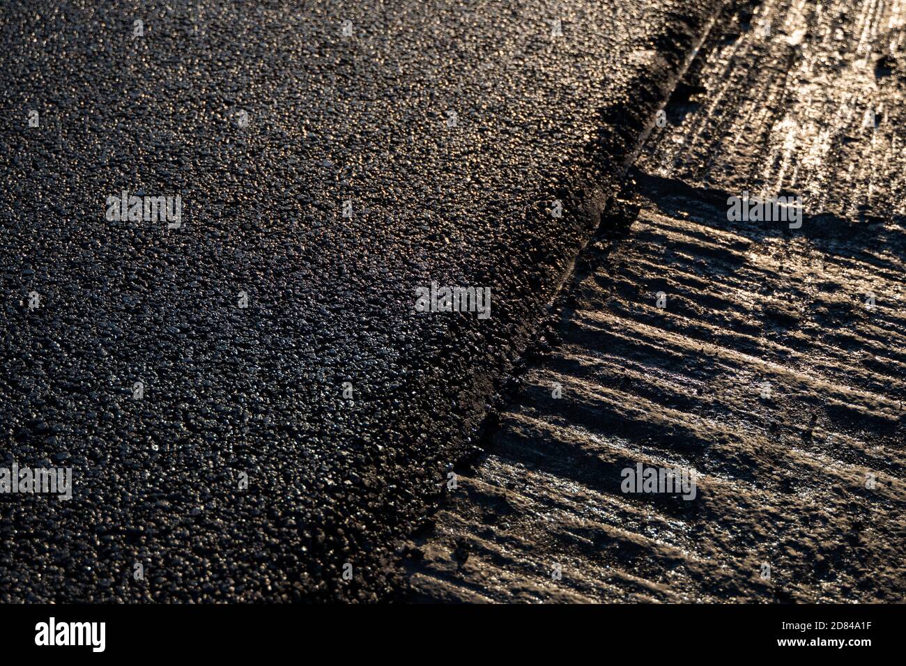Freshly laid black bitumen asphalt with a high edge to the gravel ...