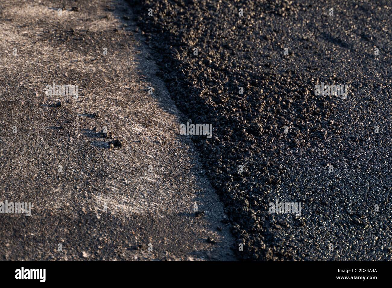 Freshly laid black bitumen asphalt with a high edge to the gravel ...