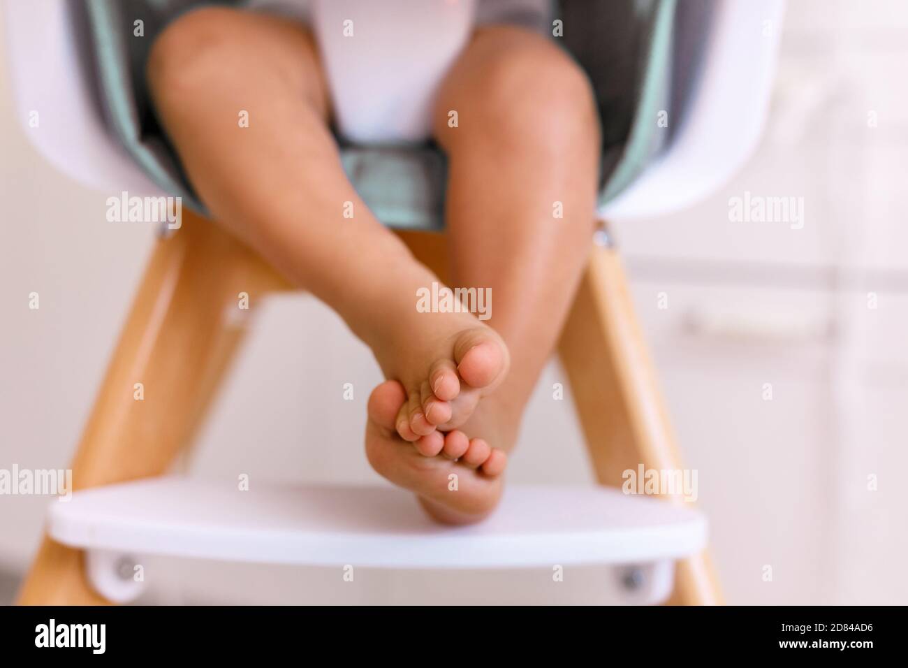 One years old child's feet on high chair while he is eating at kitchen ...