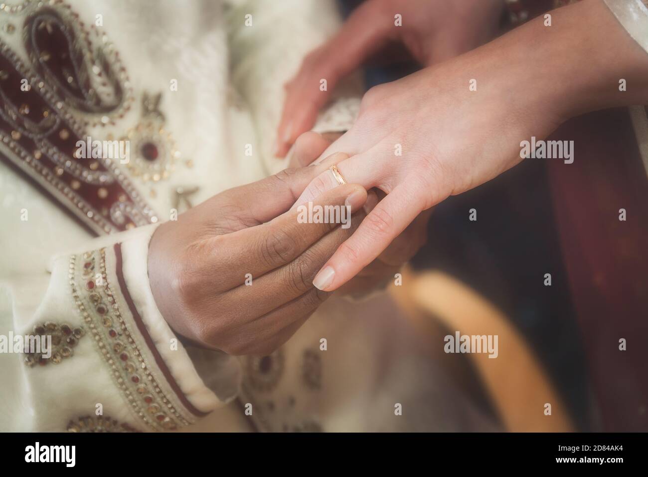 Indian groom putting ring on a brides hand during wedding ceremony ...