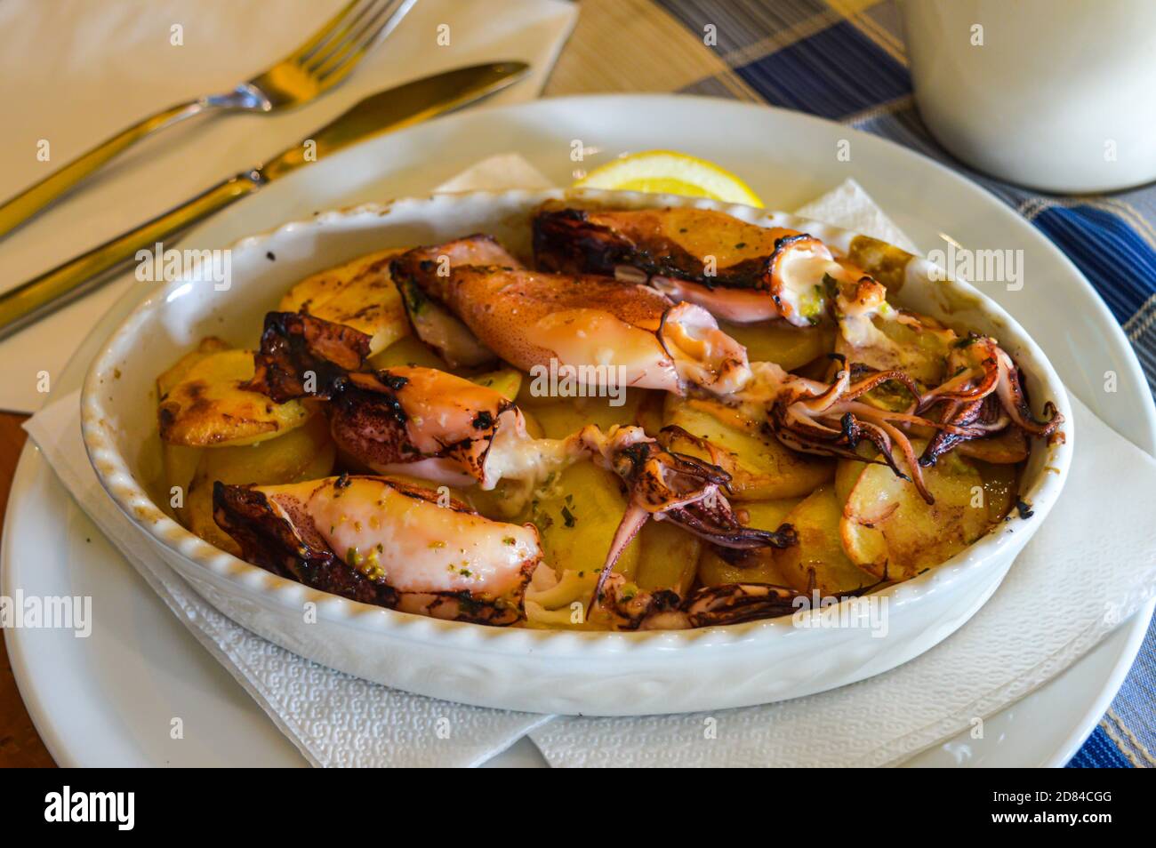 Roasted calamari with potatoes and lemon Stock Photo - Alamy