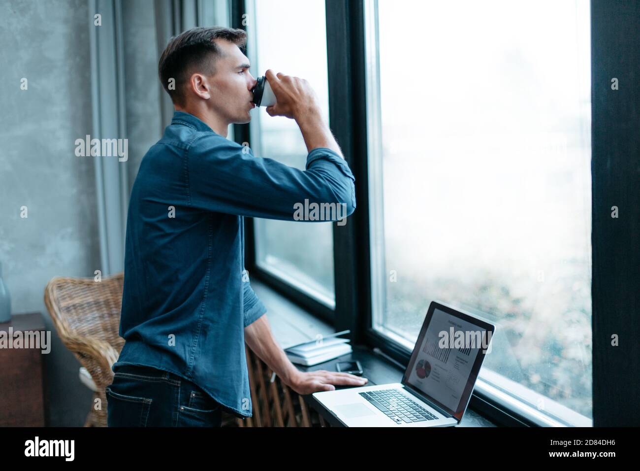 young man with takeaway coffee standing near the window Stock Photo - Alamy