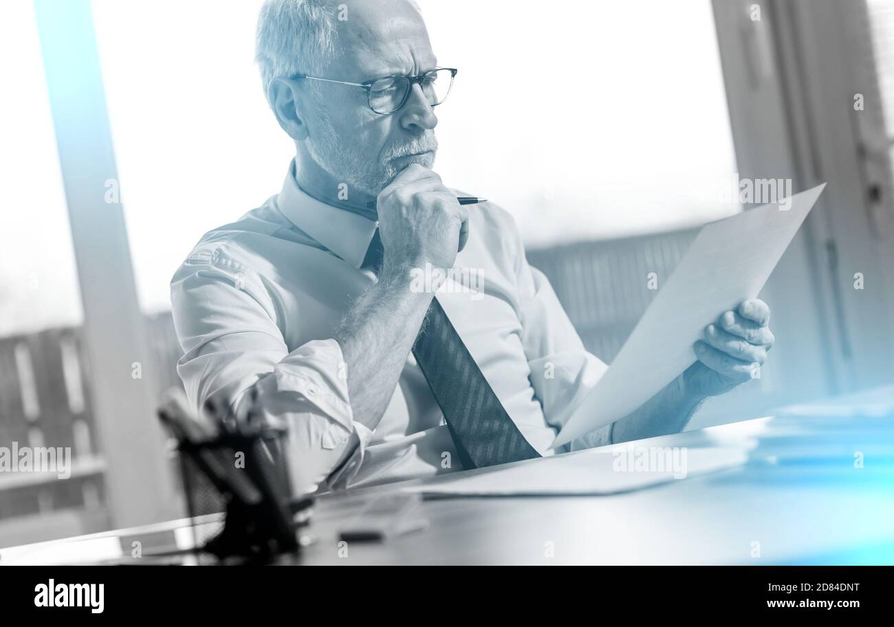 Businessman checking a document in office; light effect Stock Photo - Alamy