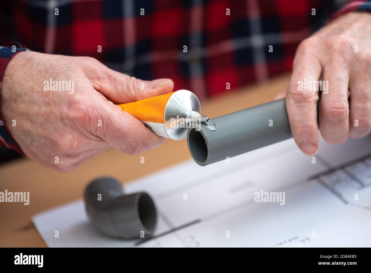 Plumber putting glue on a pvc pipe Stock Photo - Alamy