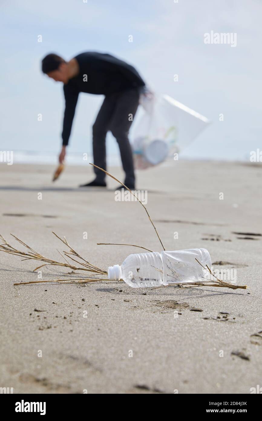 Man cleaning beach from garbage Stock Photo - Alamy
