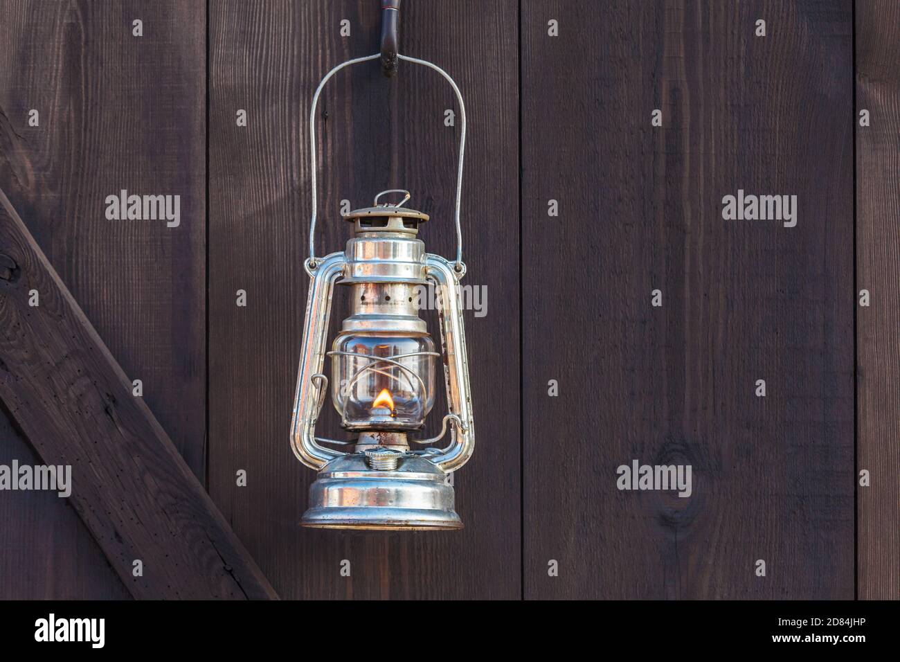 Old fashioned lantern with flame on a brown wooden wall Stock Photo - Alamy