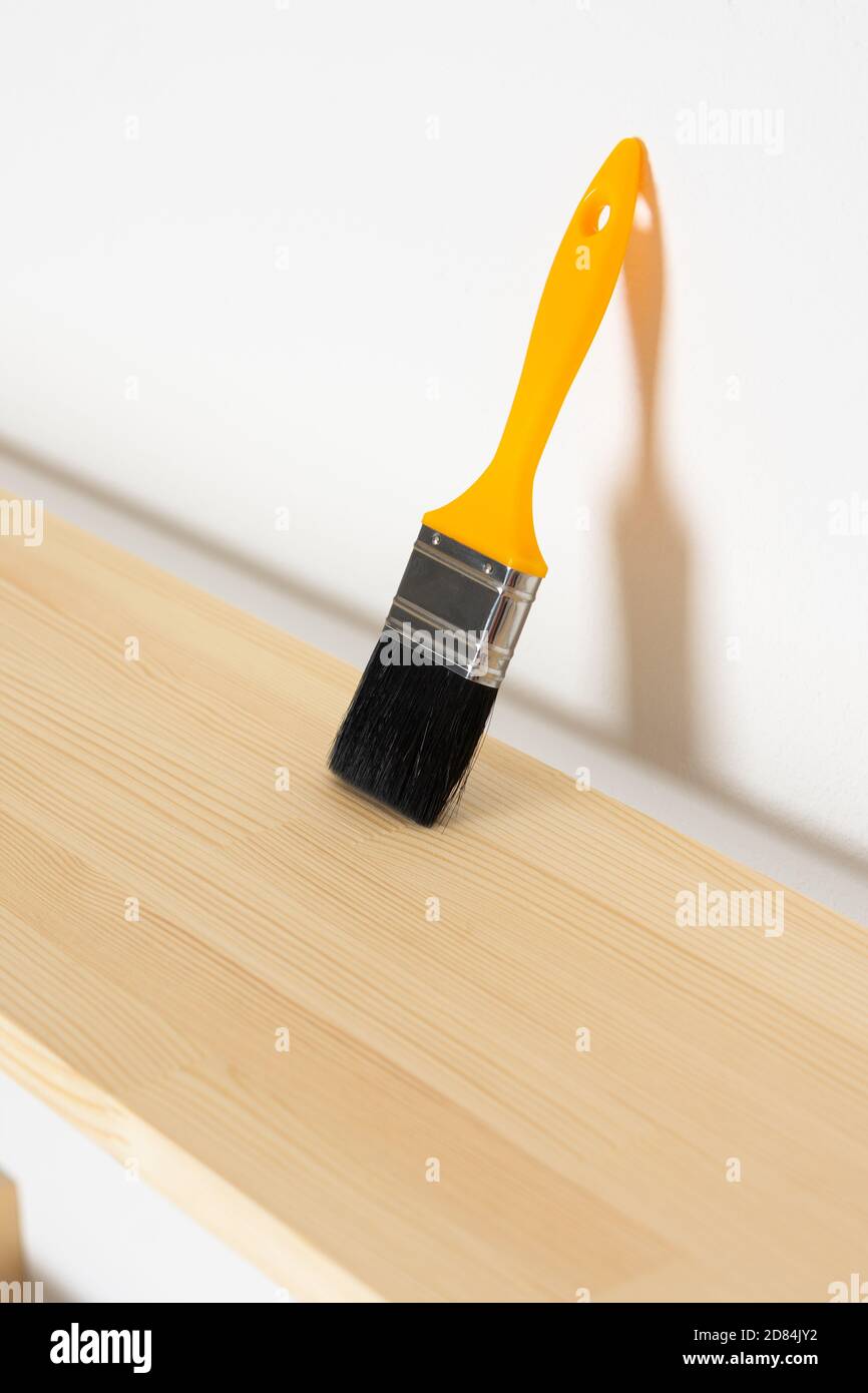 Paint brush on a wooden shelf, the process of varnishing or painting ...
