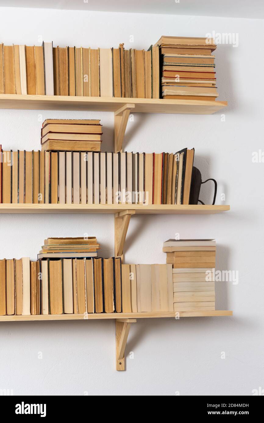 Light wooden bookshelves with hardback overturned books in white ...