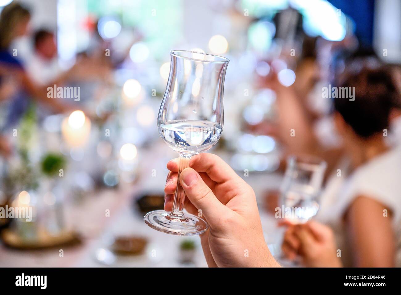 Wedding or party concept. Hand with a glass of vodka guest makes a ...