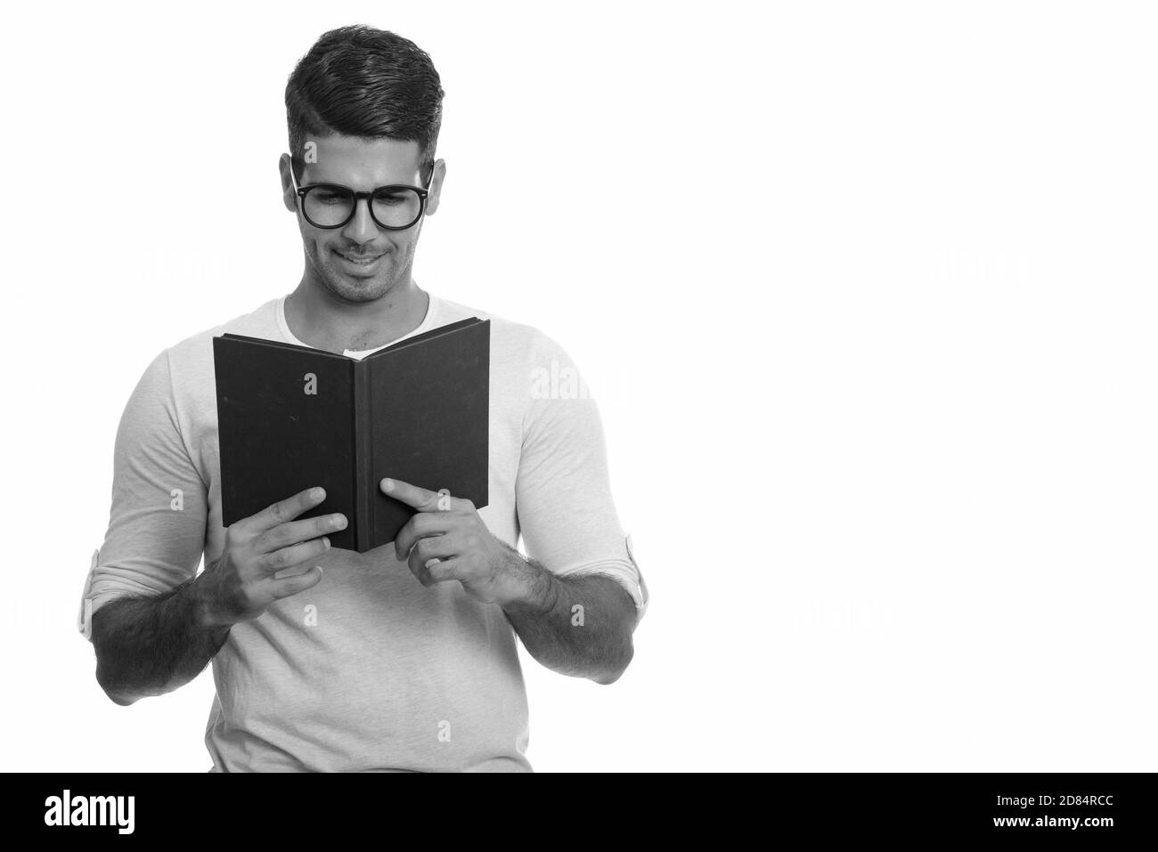 Young happy Persian man smiling while reading book Stock Photo - Alamy