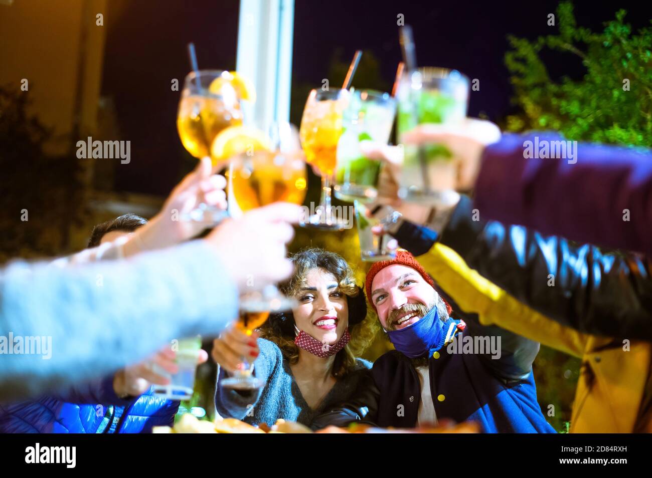 Friends drinking spritz and mojito in a cocktail bar with face masks ...