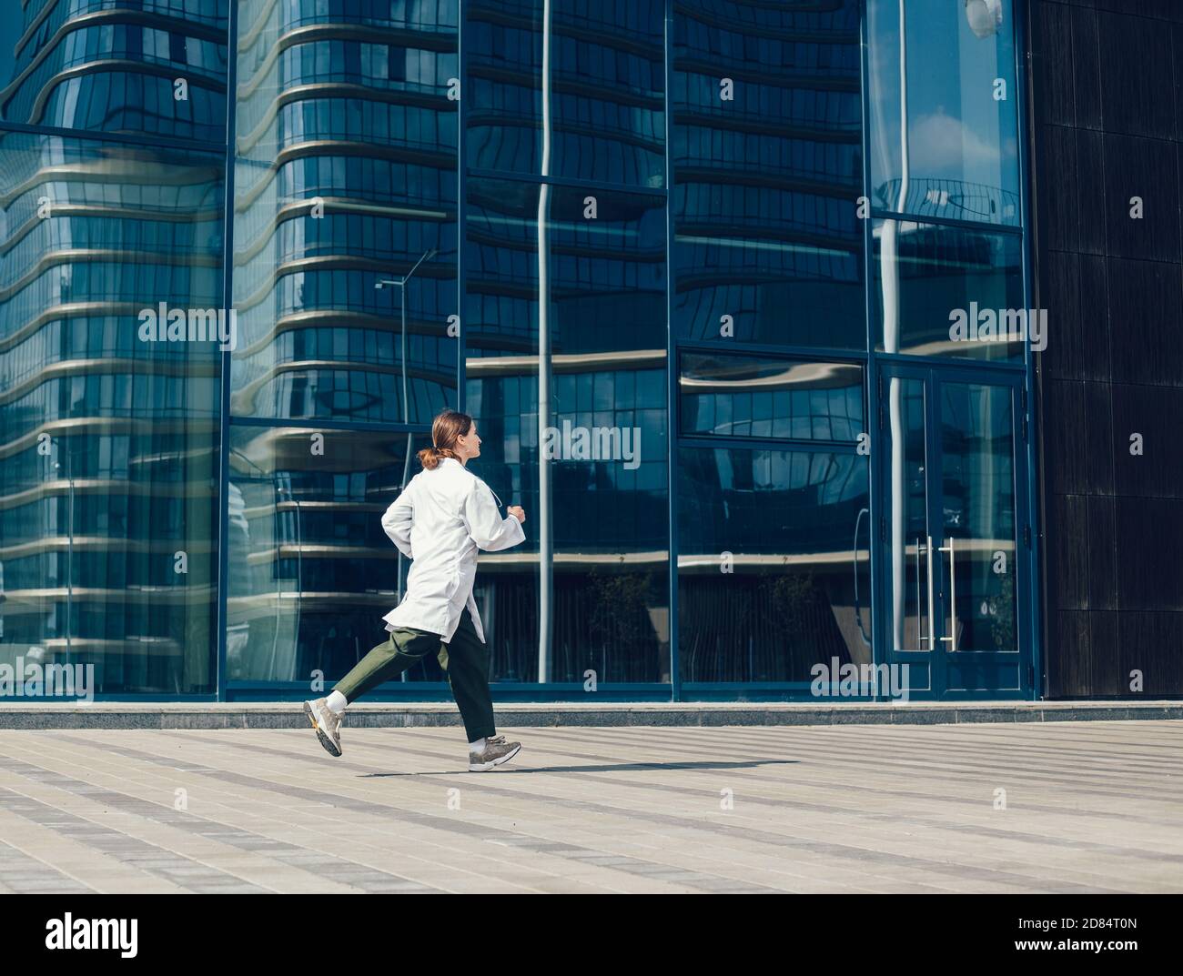 concerned woman doctor running near a city building Stock Photo - Alamy