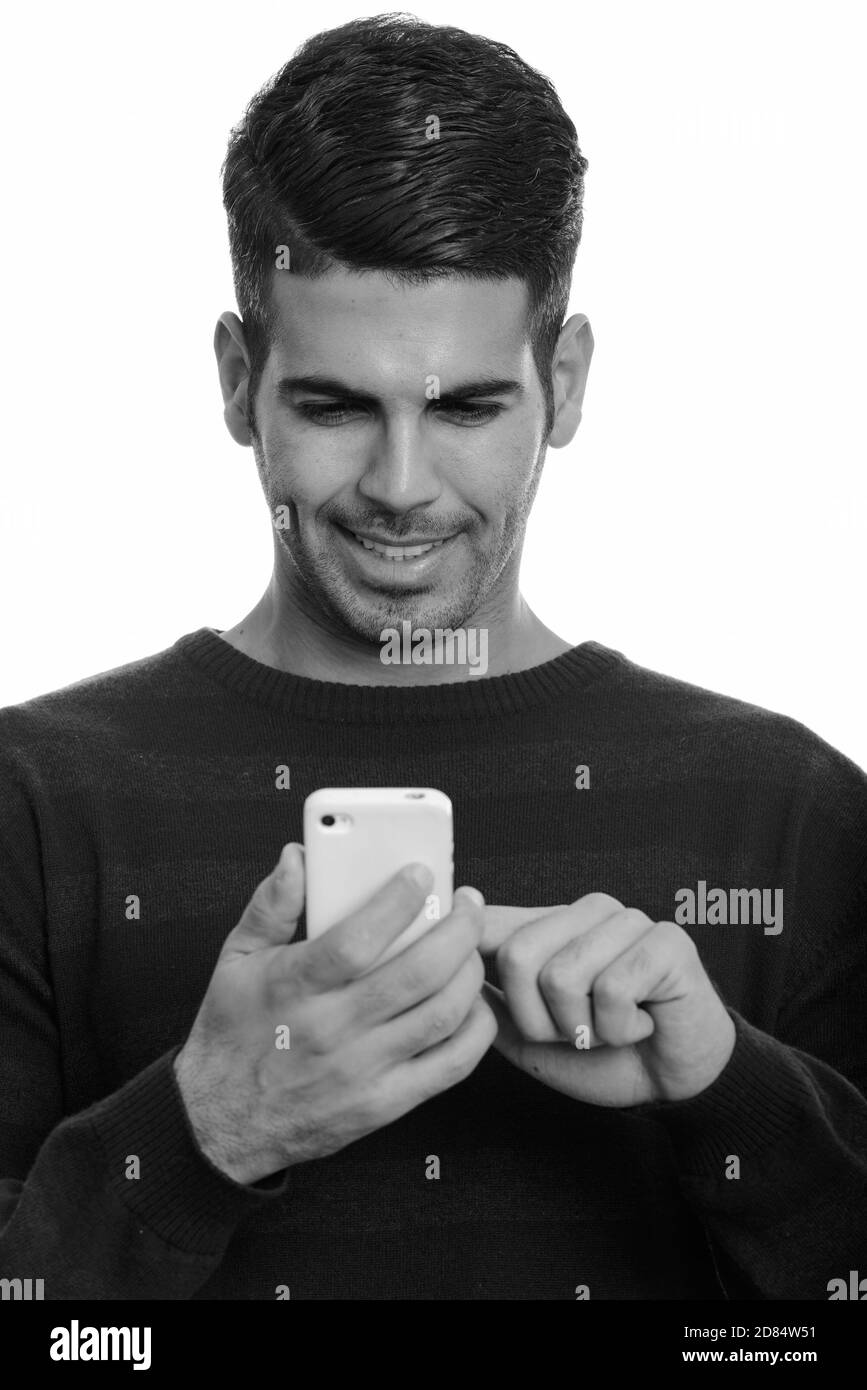 Face of young happy Persian man smiling and using mobile phone touching ...