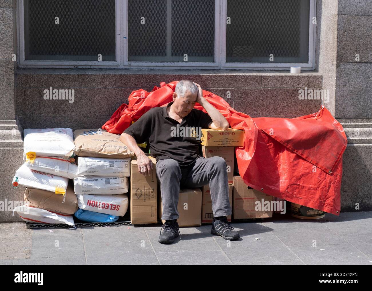 Old shopkeeper sitting and sleeping on his goods in Chinatown, London ...