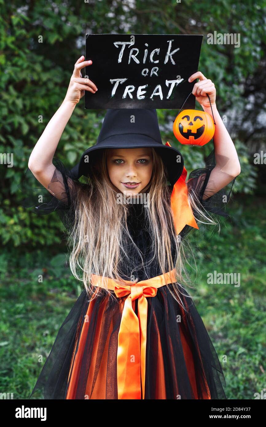 Little girl in witch costume trick or treating outdoor. Happy Halloween ...