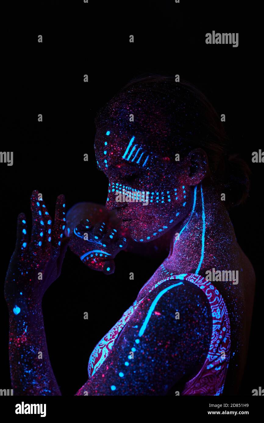 Art woman cosmos in ultraviolet light. Entire body is covered with colored droplets. Girl posing ...