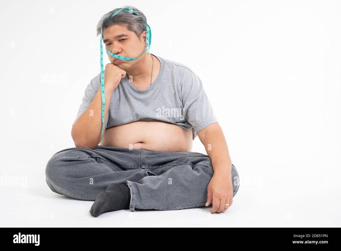 An overweight man sitting on the floor and Bored after uses a ...
