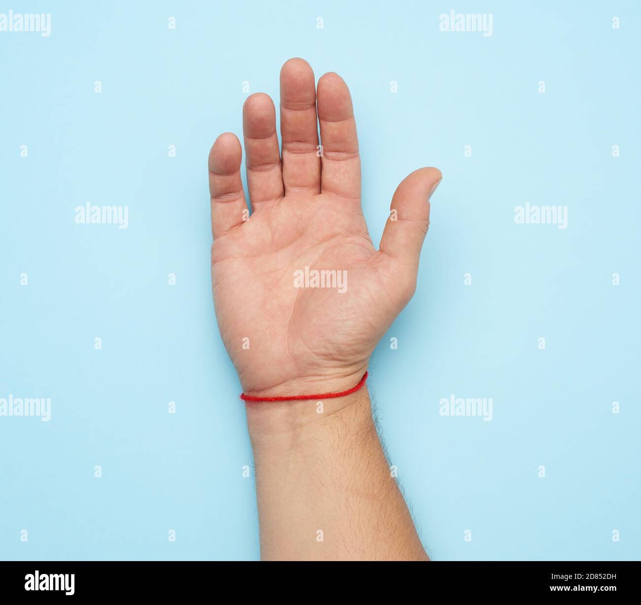 red woolen thread on the wrist of a male hand, blue background, top ...