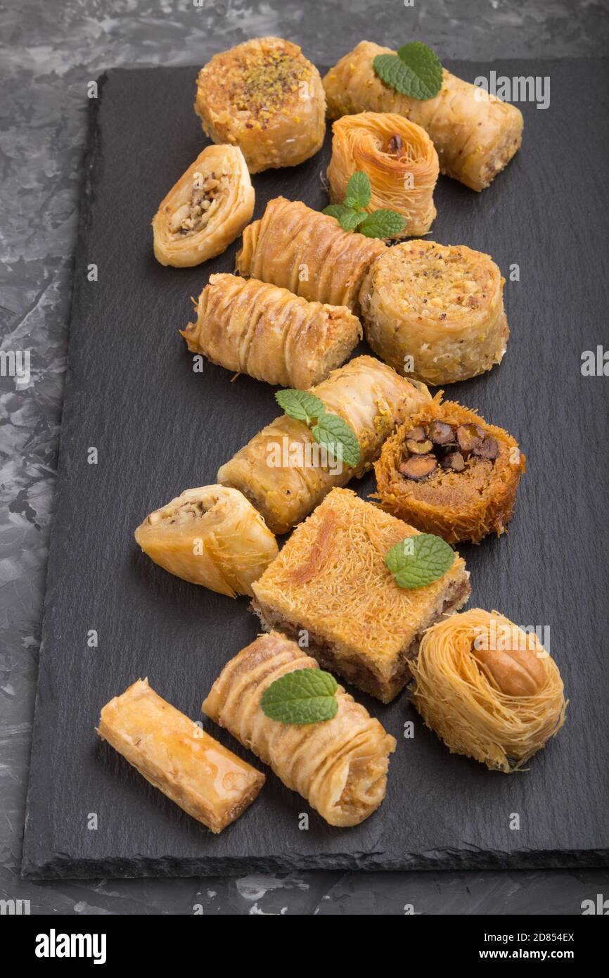 traditional arabic sweets (kunafa, baklava) on a black slate board on a ...