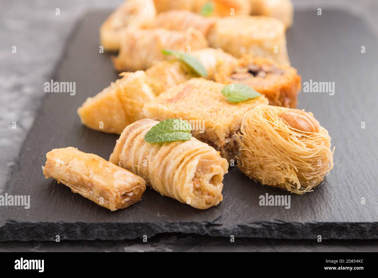 traditional arabic sweets (kunafa, baklava) on a black slate board on a ...