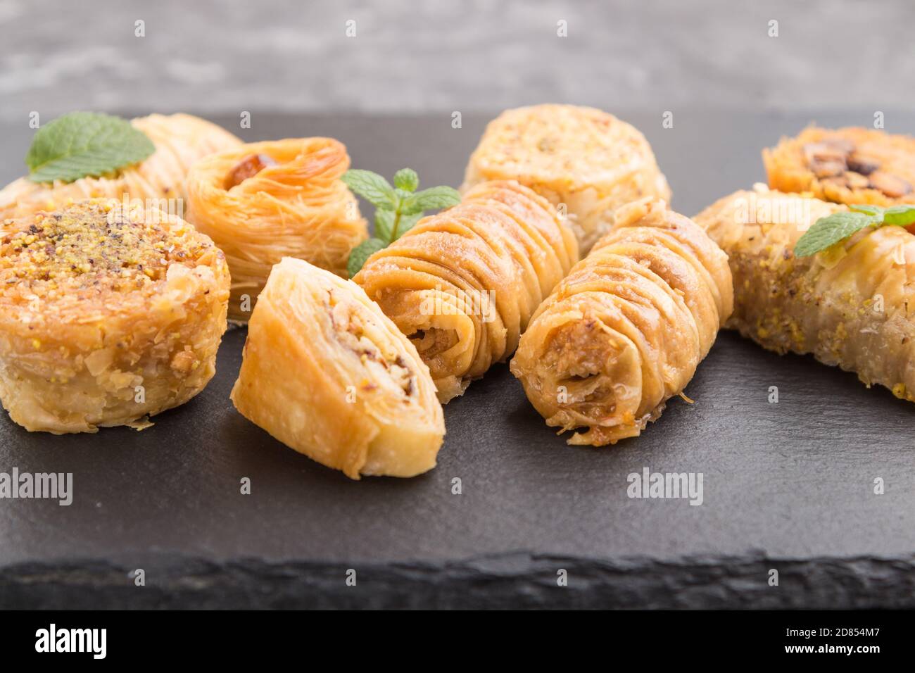 traditional arabic sweets (kunafa, baklava) on a black slate board on a ...