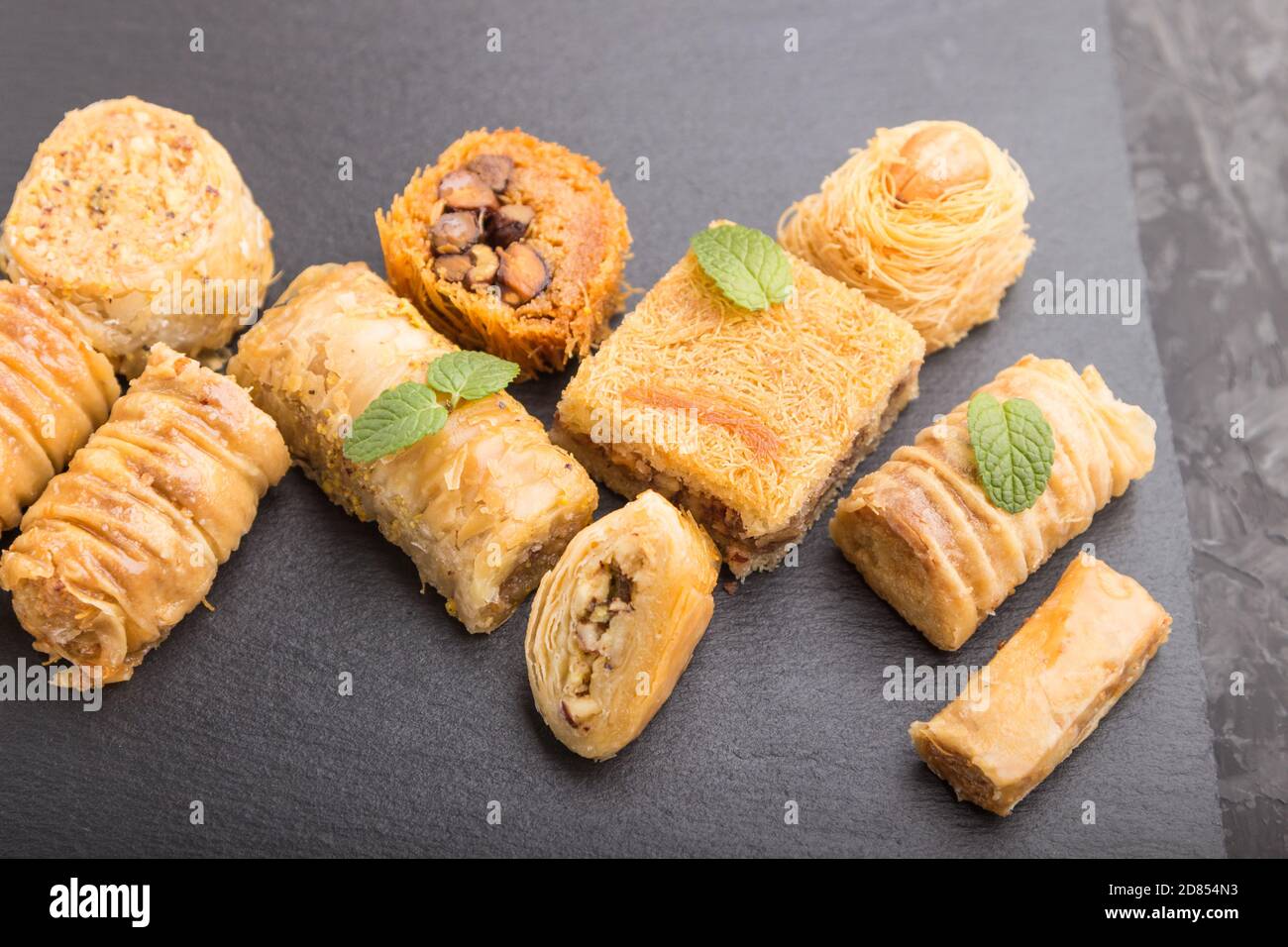 traditional arabic sweets (kunafa, baklava) on a black slate board on a ...