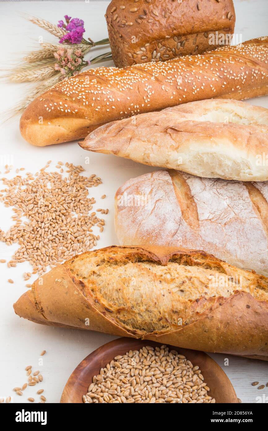 Different kinds of fresh baked bread on a white wooden background. side ...