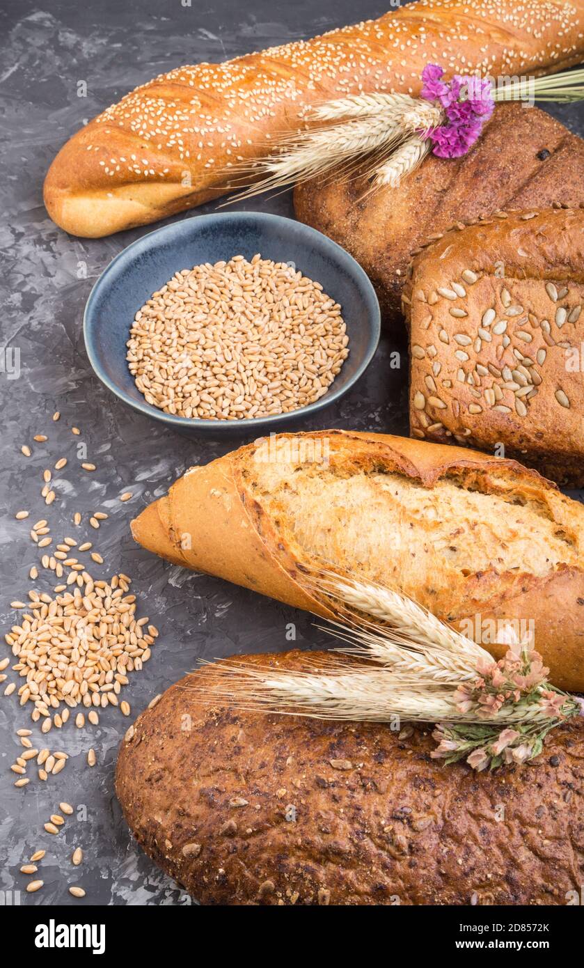 Different kinds of fresh baked bread on a black concrete background ...