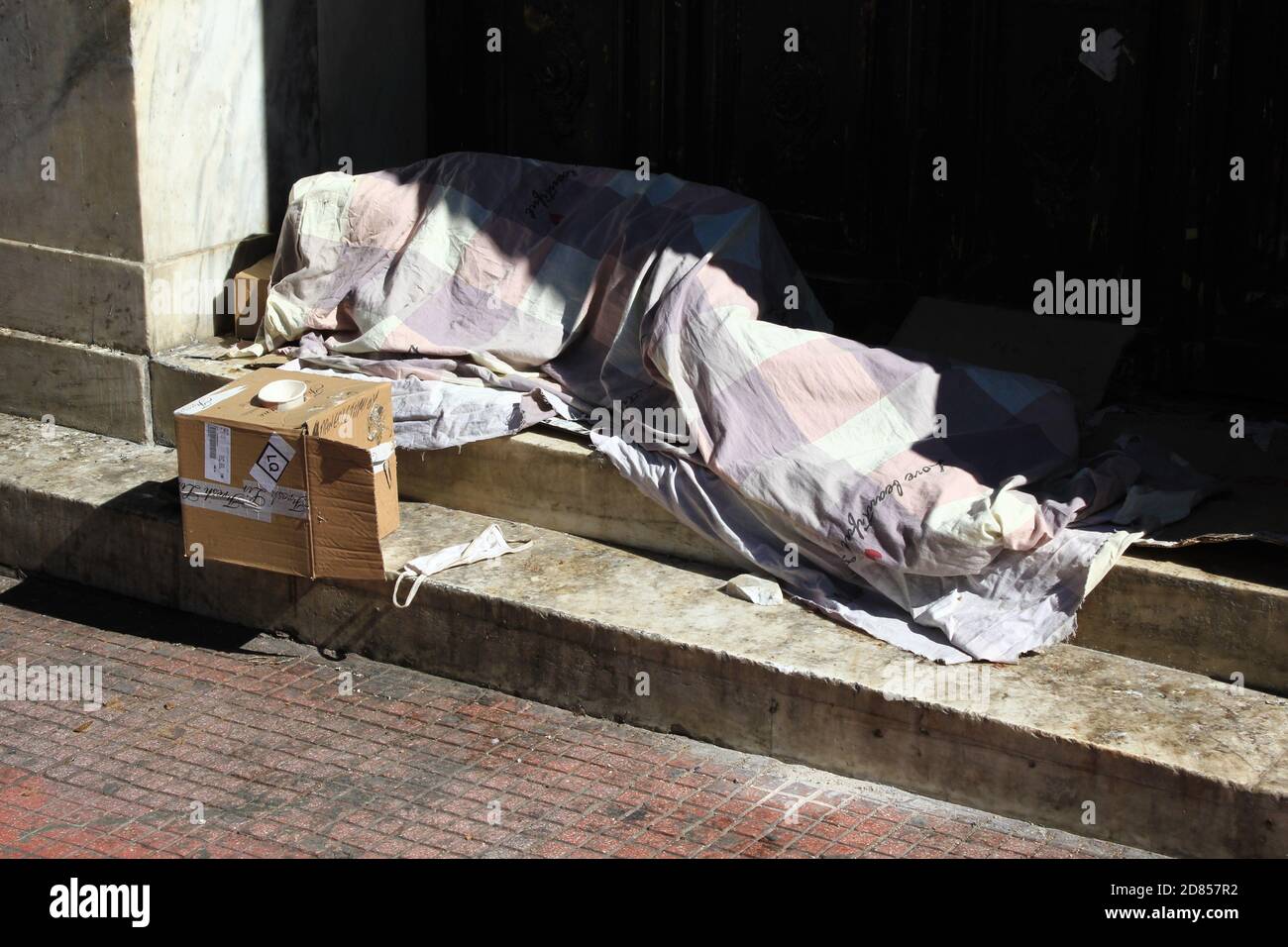 An unidentified homeless person sleeping in front of the entrance of ...