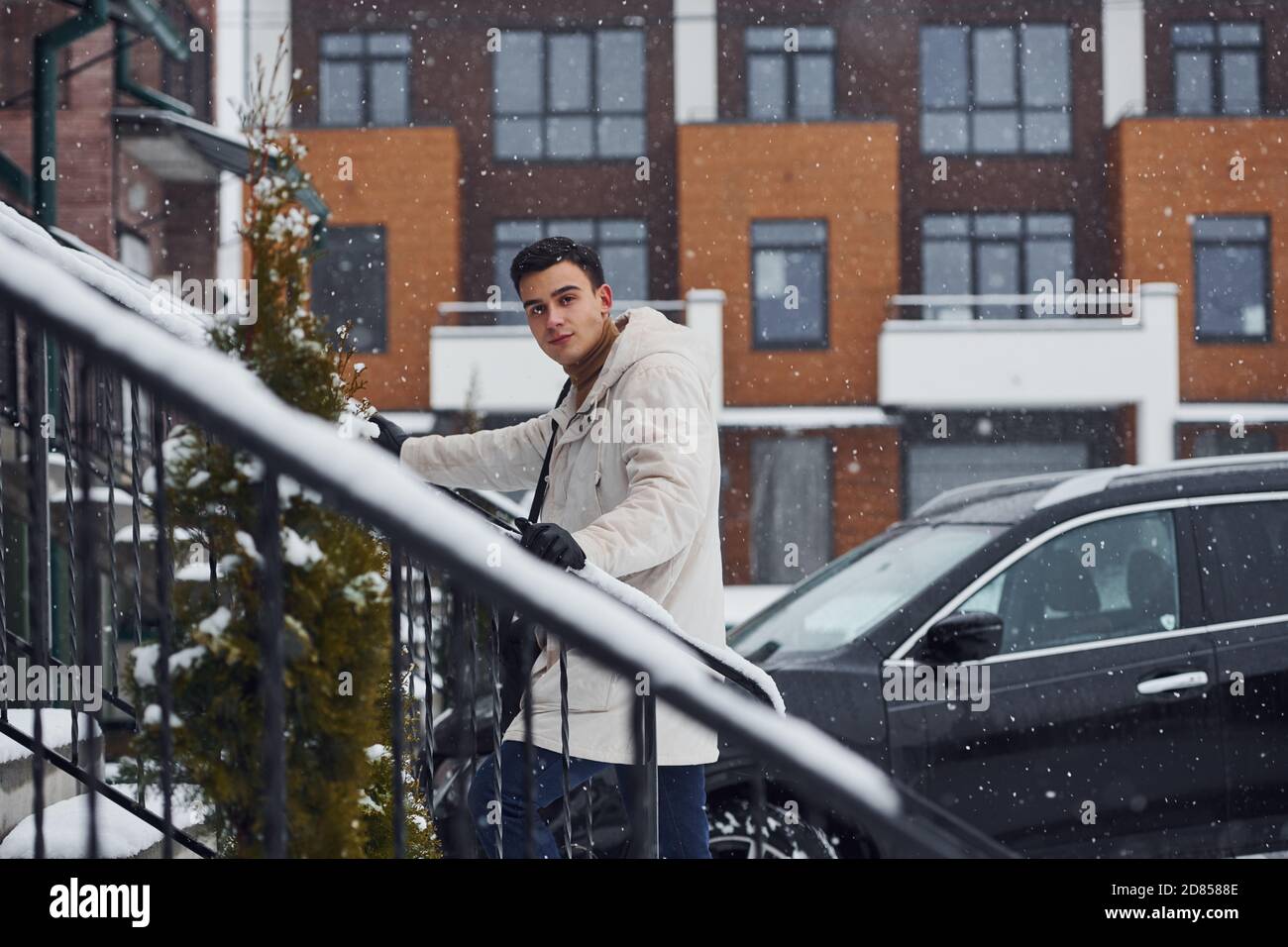 Man with christmas tree standing on the ladder of building near car ...