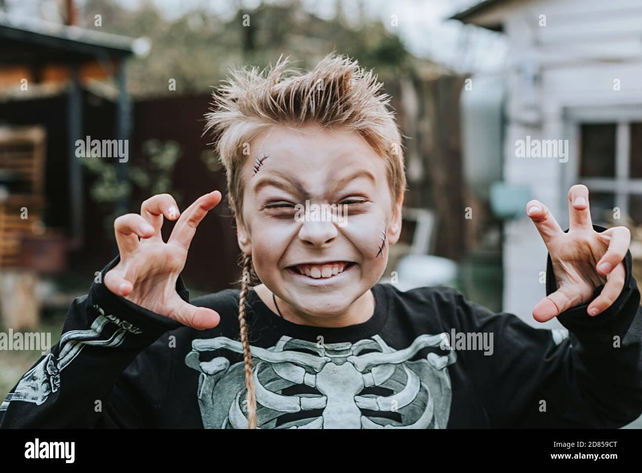 a boy in a skeleton costume with a painted face on the porch of a house ...