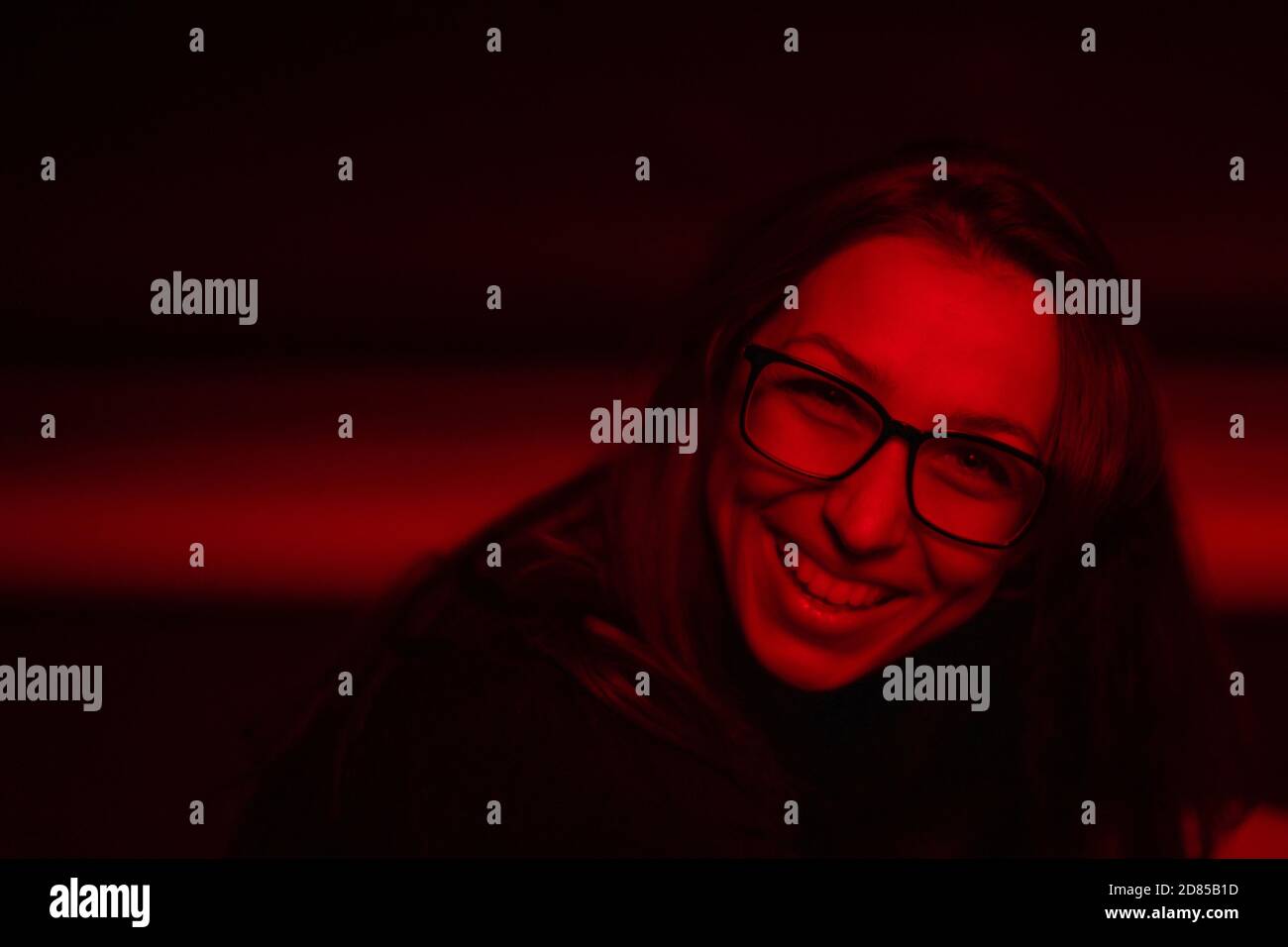 Low key full-face portrait of smiling Jewish girl in glasses in red ...