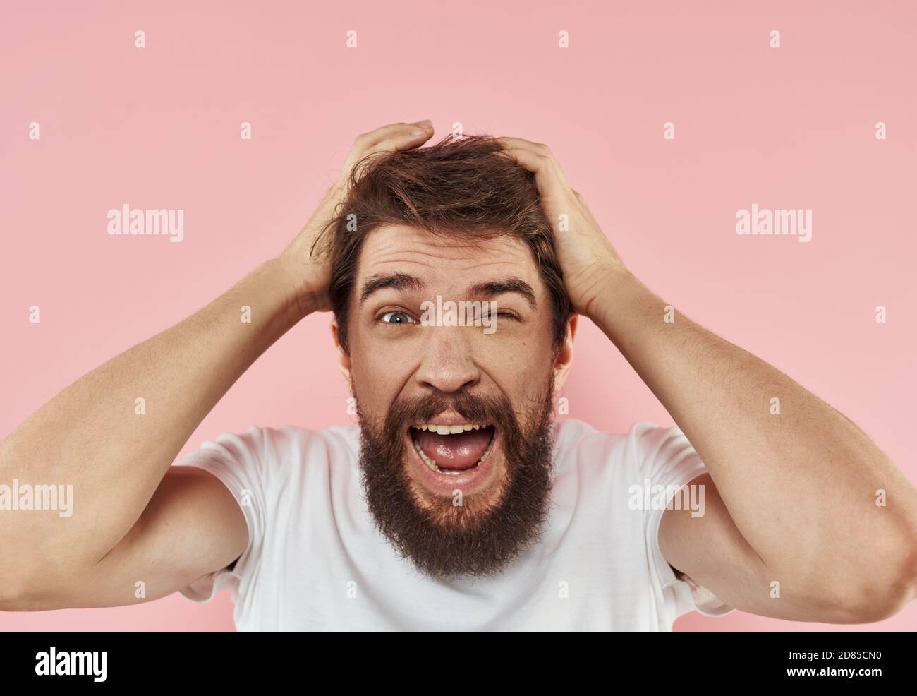 Portrait of an energetic guy on a pink background in a white t-shirt ...