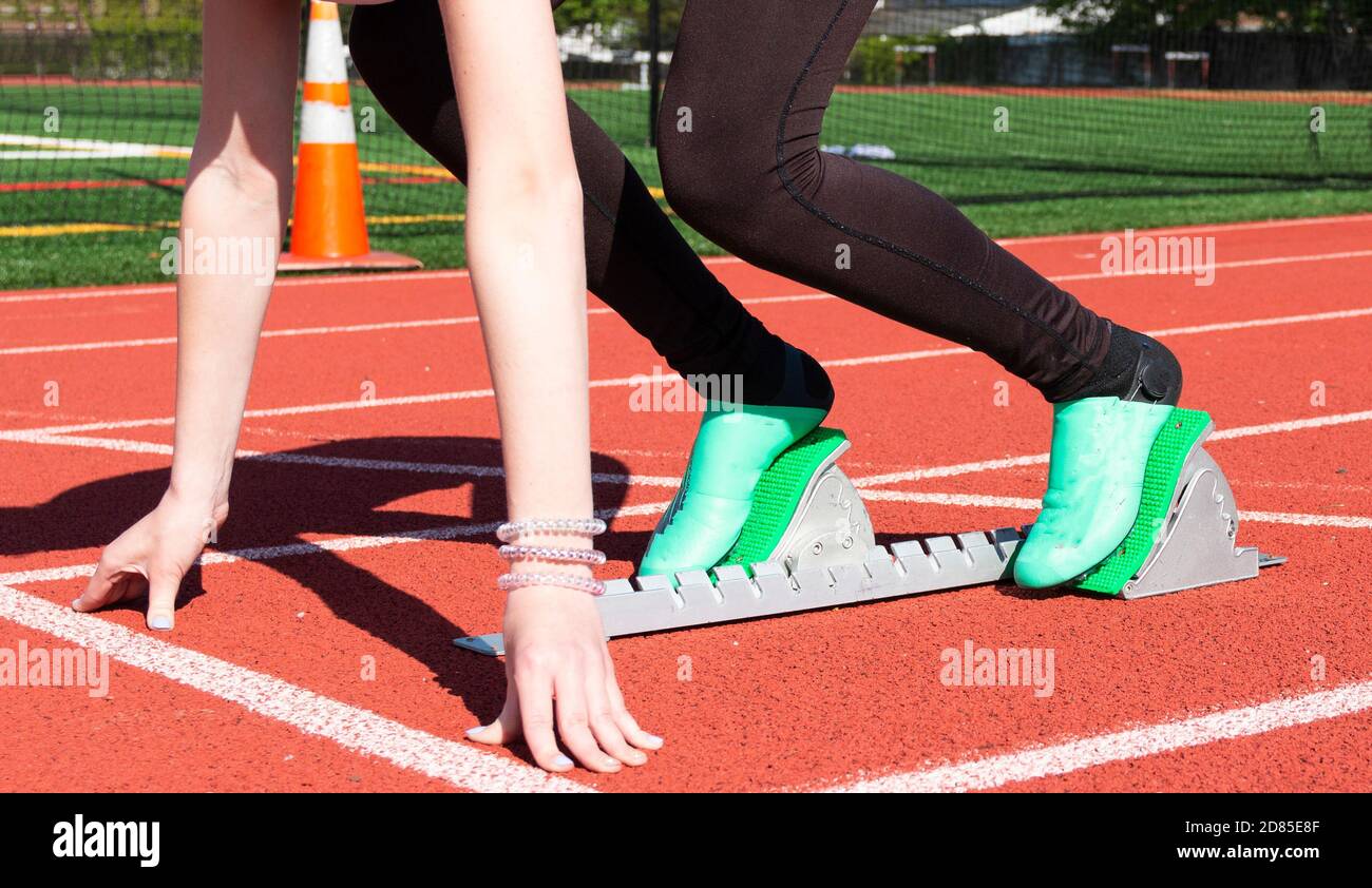 A high school girl is in the set position in a set of starting blocks ...
