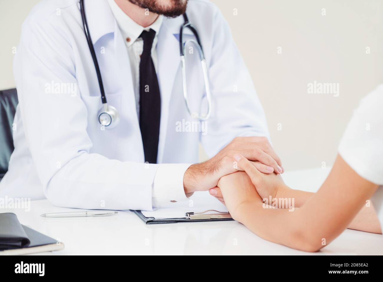 Male Doctor Soothes A Female Patient In Hospital Office While Holding