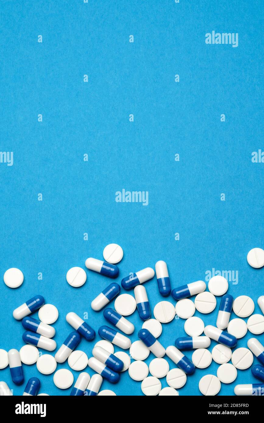 group of pills or capsules on blue background Stock Photo - Alamy