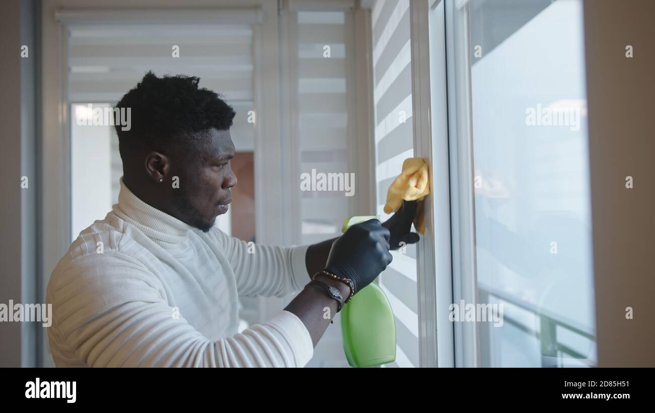 Young african american black man washing the window frames. High ...
