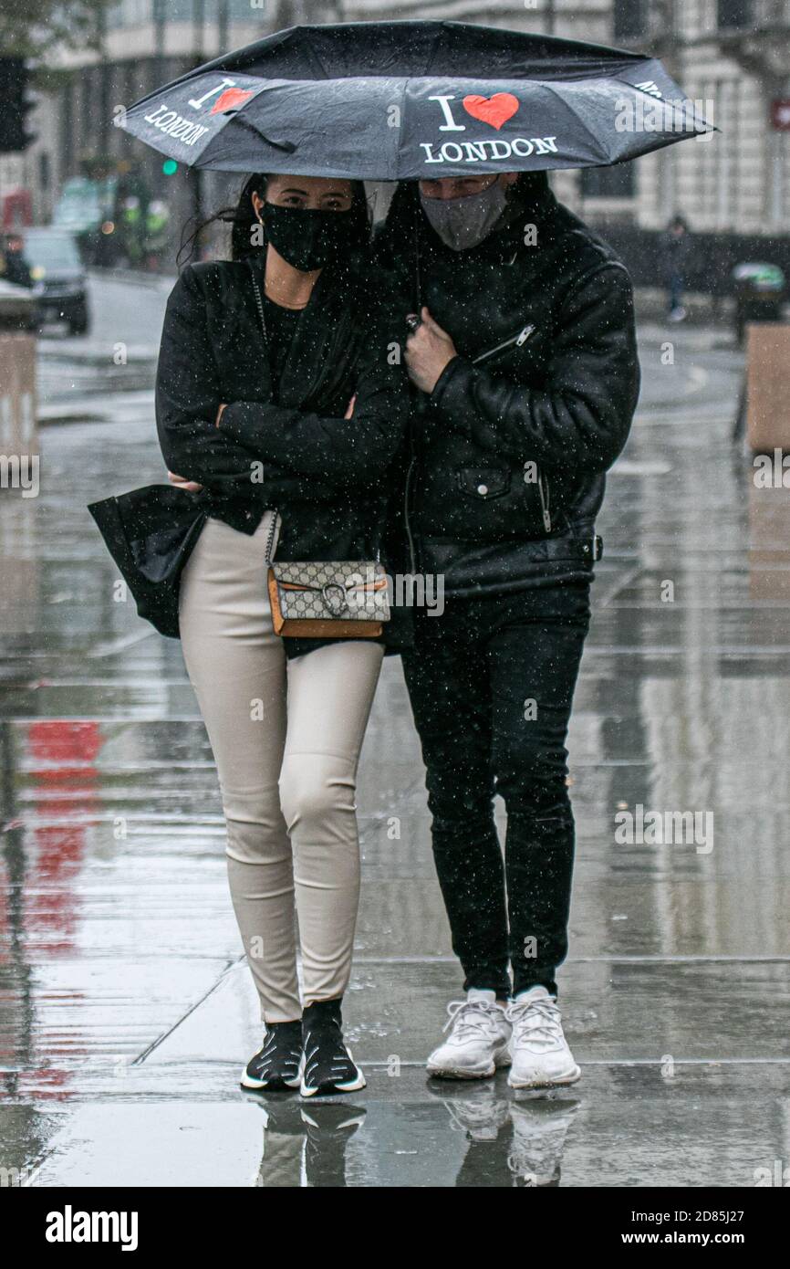 LONDON,UK 27 October 2020. Pedestrians in Trafalgar Square sheltering ...