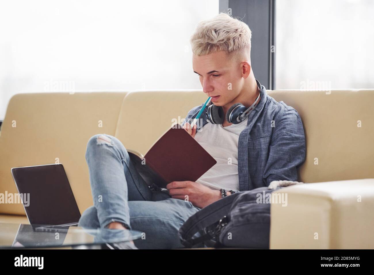 Young hipster guy in nice clothes sitting on sofa with notepad Stock ...