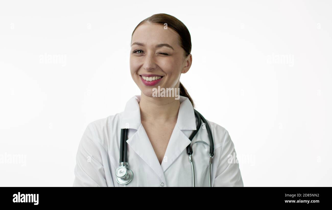 Female doctor smiles broadly with a snow-white smile and winks ...