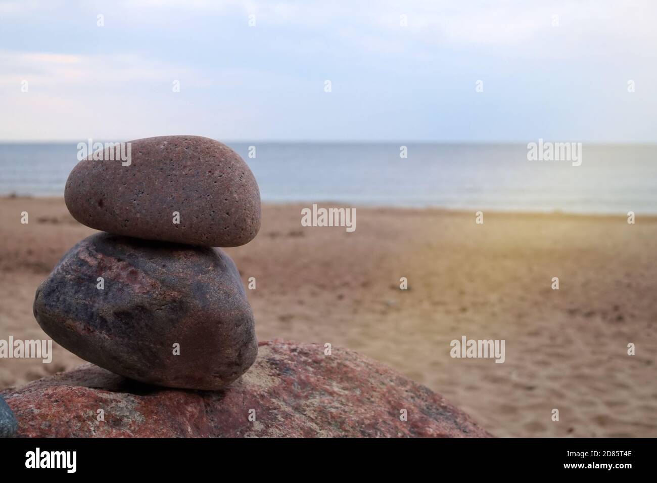 Two stacked natural rocks on top of a boulder on a sandy tropical beach ...