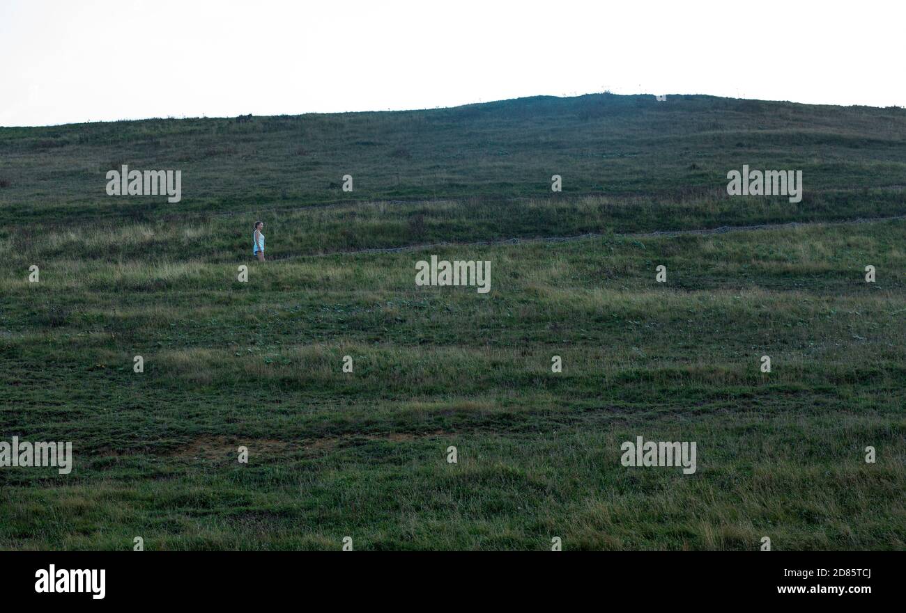 Woman walking alone in field, Whitby, England, UK Stock Photo - Alamy