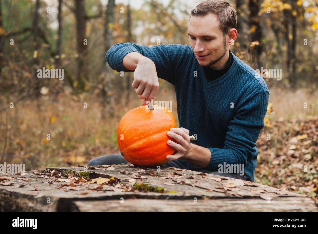 A young man carves the face of a pumpkin in out door Stock Photo - Alamy