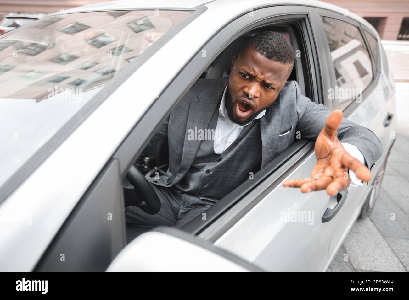 Furious black businessman gesturing and shouting while driving car ...